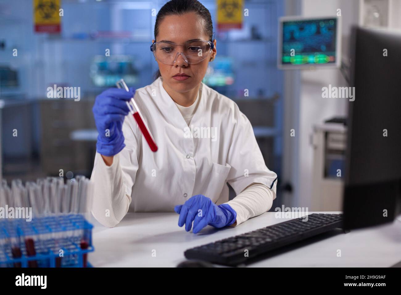 Chemist researcher holding test tubes with patient blood working at ...