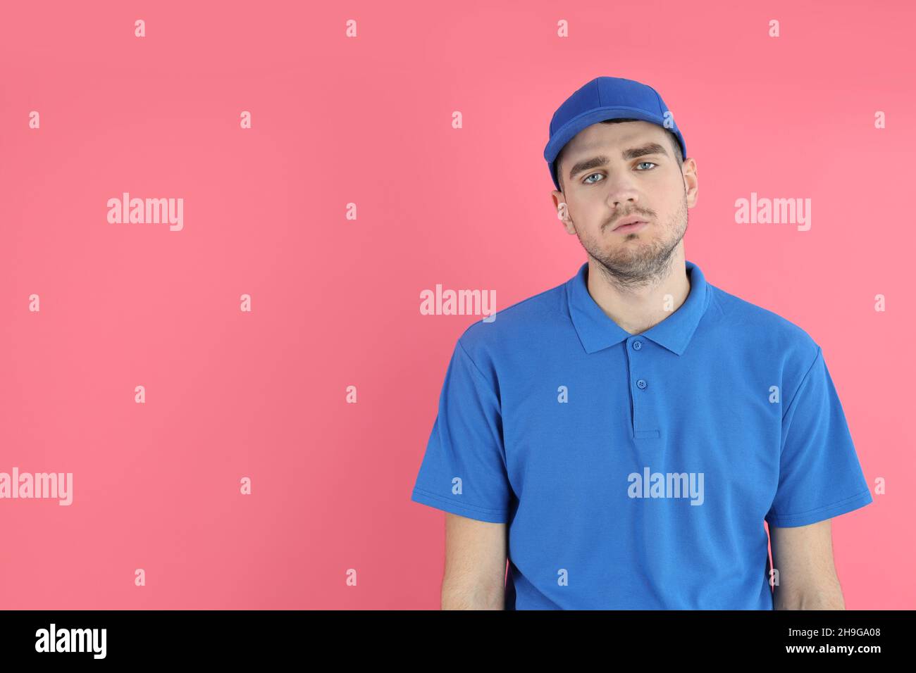 Tired delivery man in cap and t-shirt on pink background Stock Photo ...