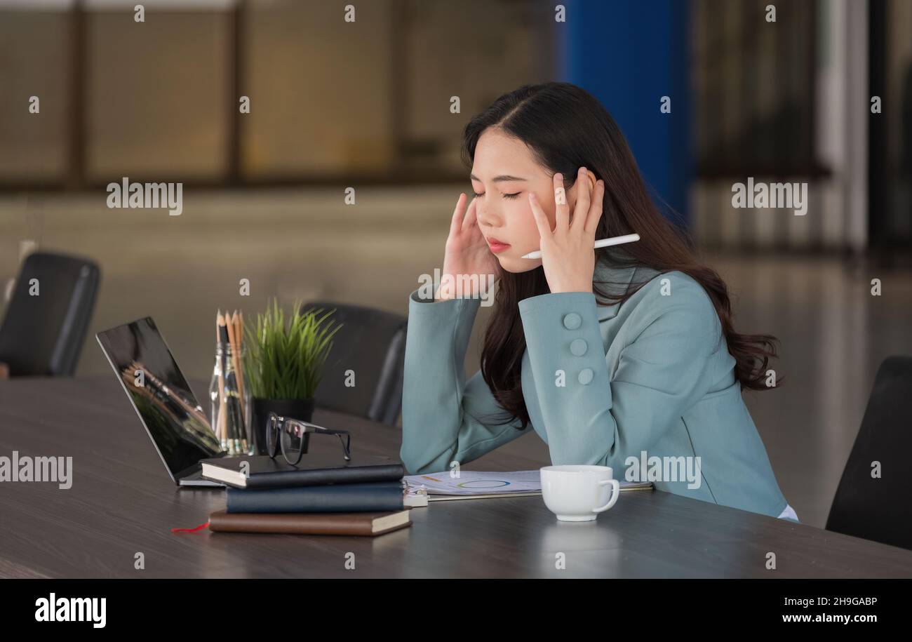Tired business asian woman with headache looking uncomfortable while ...