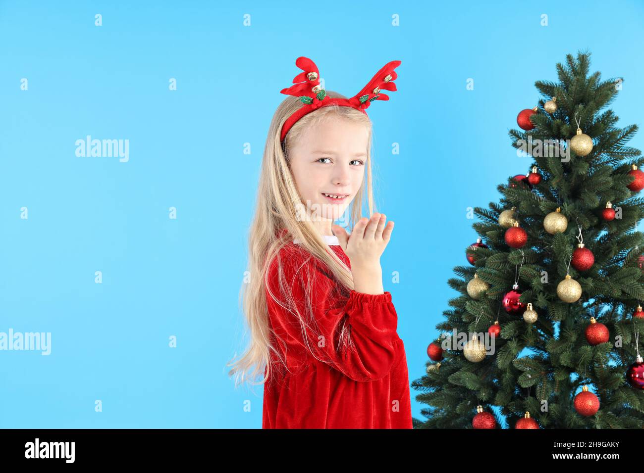 Cute little girl on blue background with Christmas tree Stock Photo - Alamy