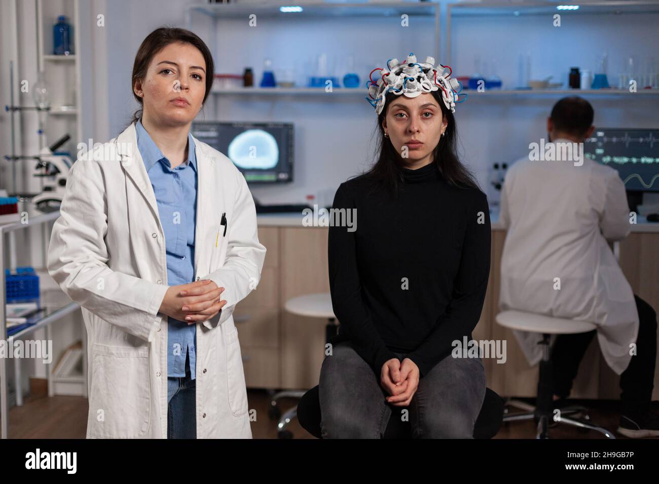Portrait of neurologist doctor standing beside woman patient with ...