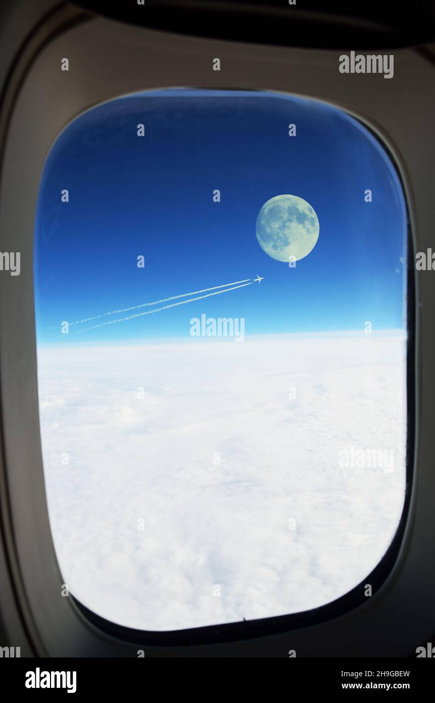 Airplane window with view cloudscape with full moon and an airplane in ...