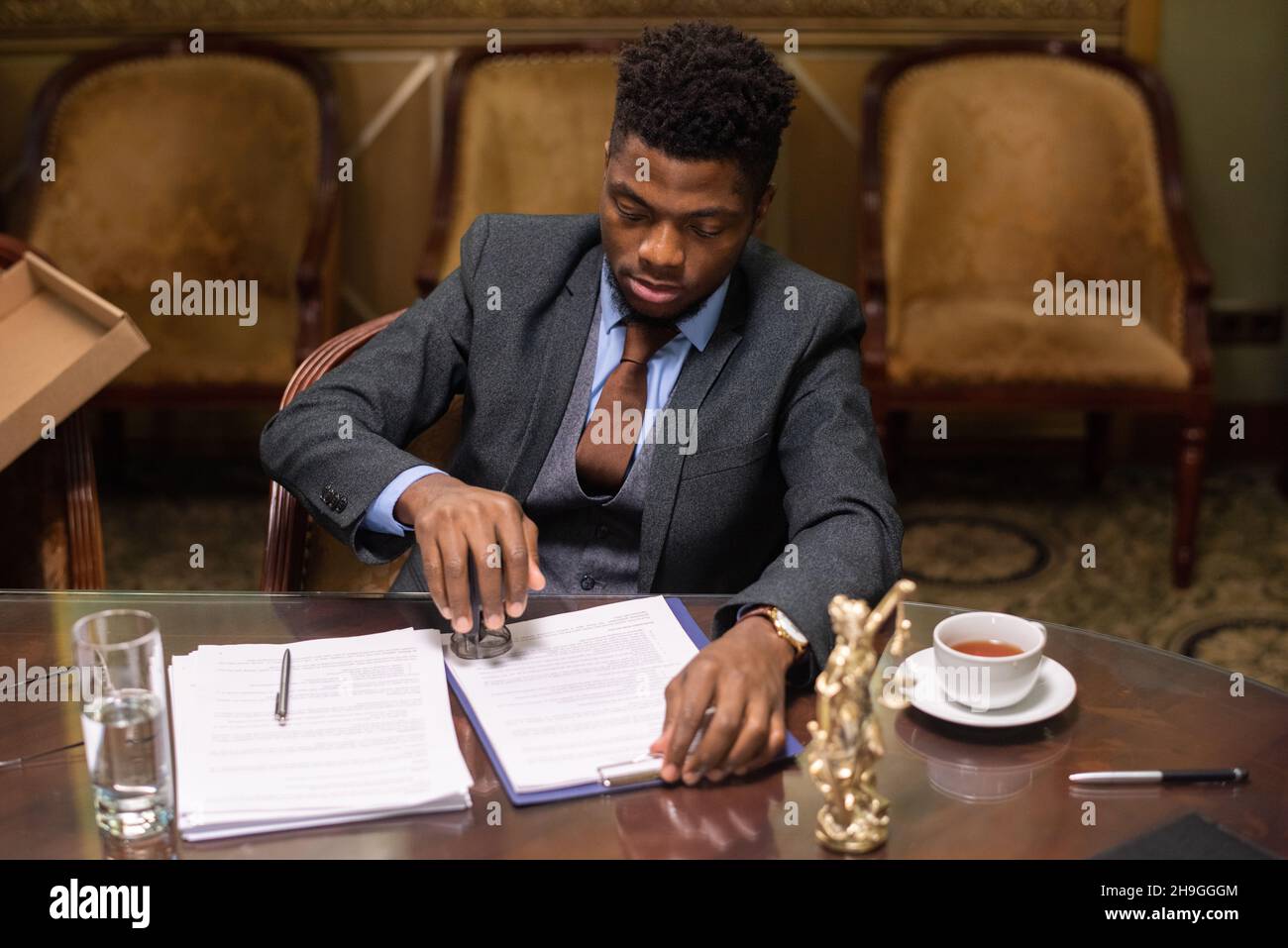 Young AFrican businessman in formalwear putting notary stamp on ...