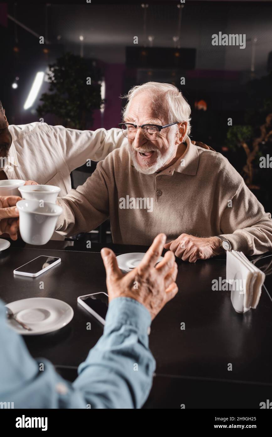senior multicultural friends clinking coffee cups while spending time ...