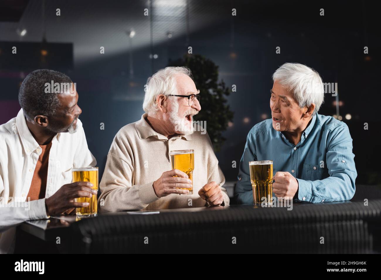 senior man laughing while drinking beer with multiethnic friends Stock ...