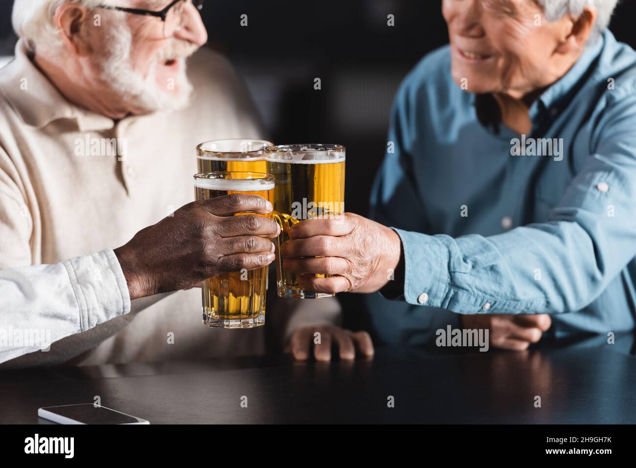 senior multiethnic friends clinking glasses of beer while spending time ...