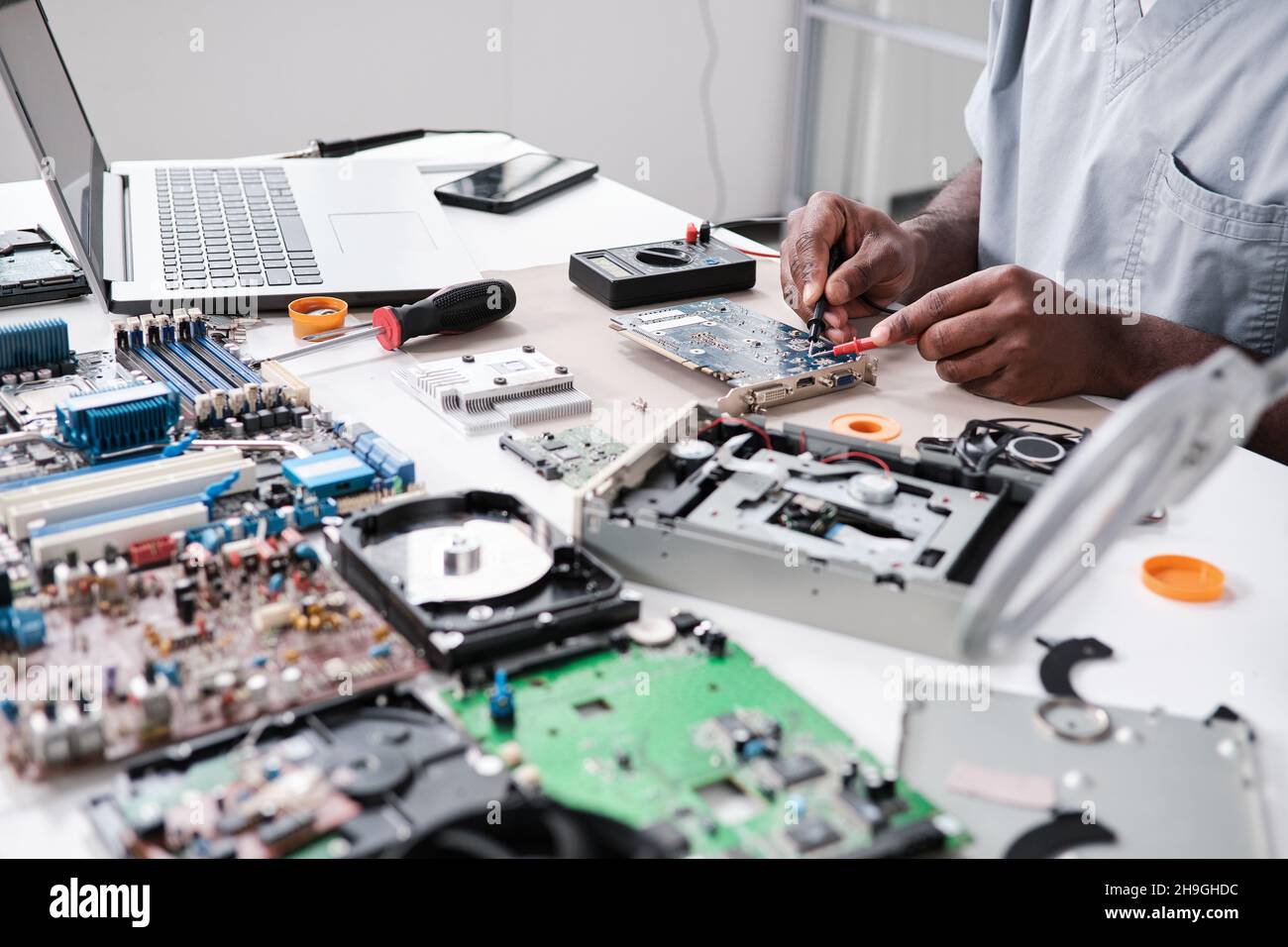 Hands of young African man repairing circuit board with soldering iron ...