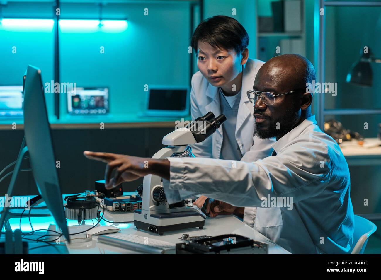 Confident African scientist pointing at computer screen while ...