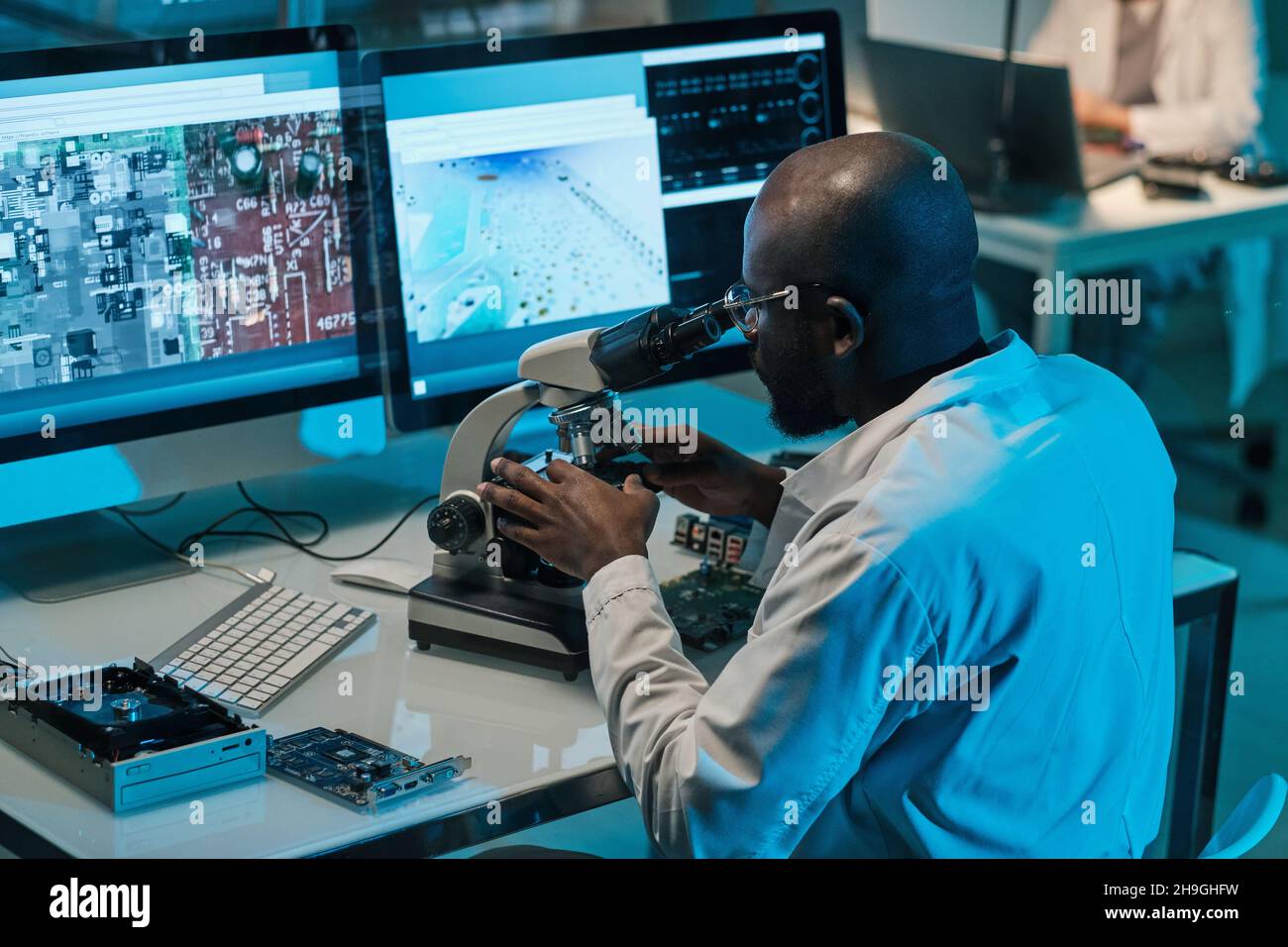 Contemporary young African scientist with microscope working in front ...