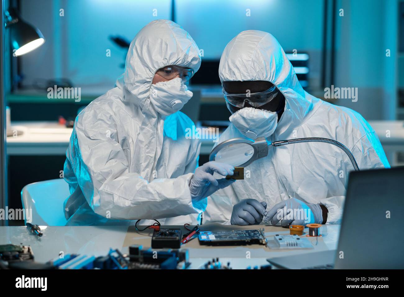 Young Asian woman in coveralls helping colleague with repairment of ...