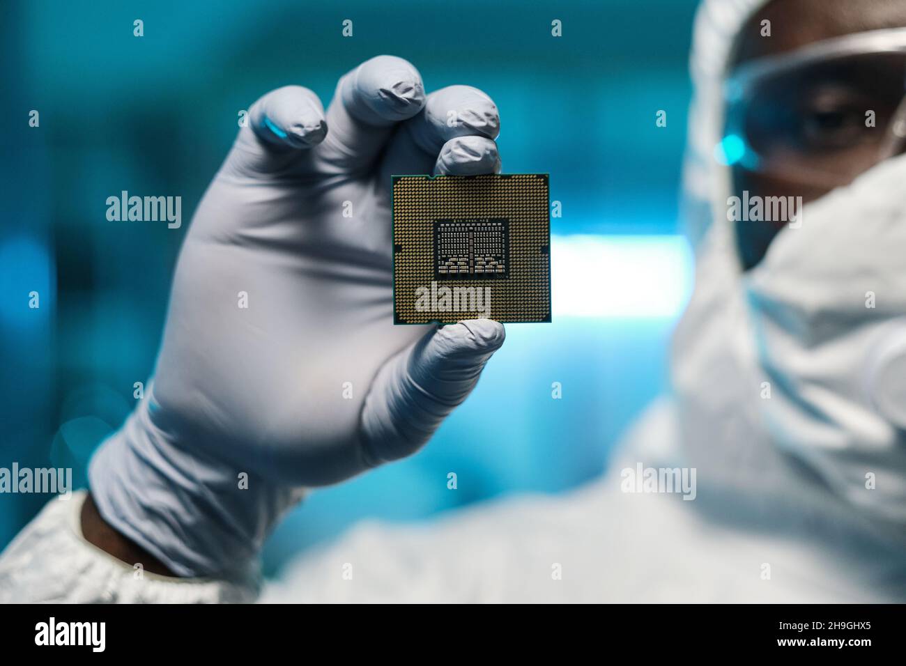 Gloved hand of African man in protective coveralls, respirator, and ...