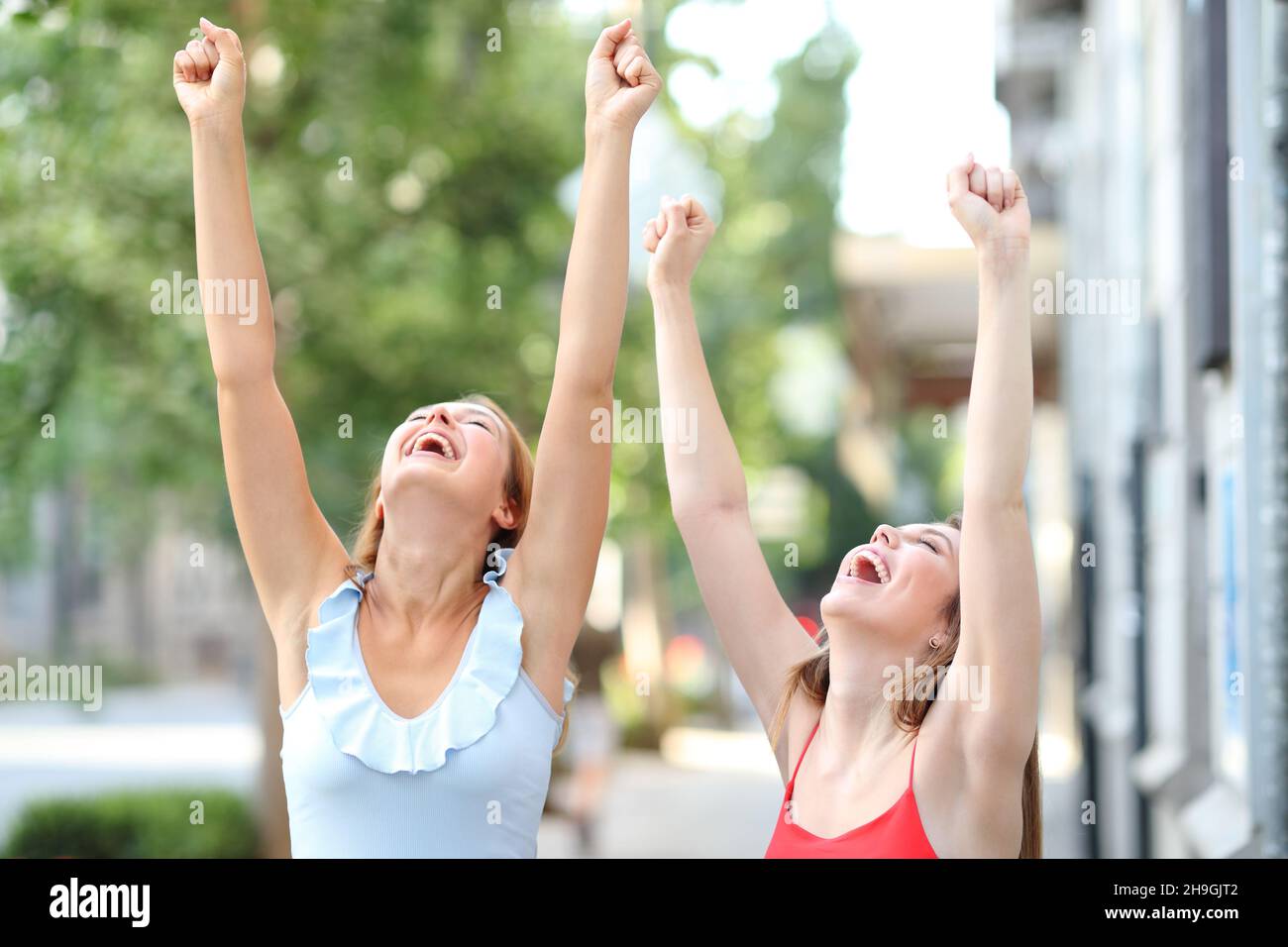 Happy friends raising arms celebrating success in the street Stock ...
