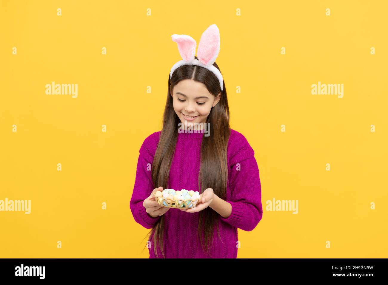 surprised teen kid in bunny ears with painted quail eggs for easter ...