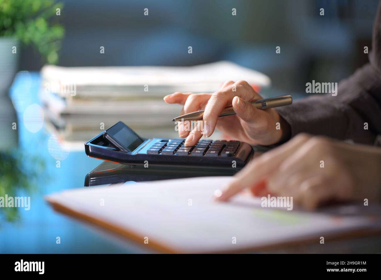 Executive hands calculating using calculator in the night at office ...
