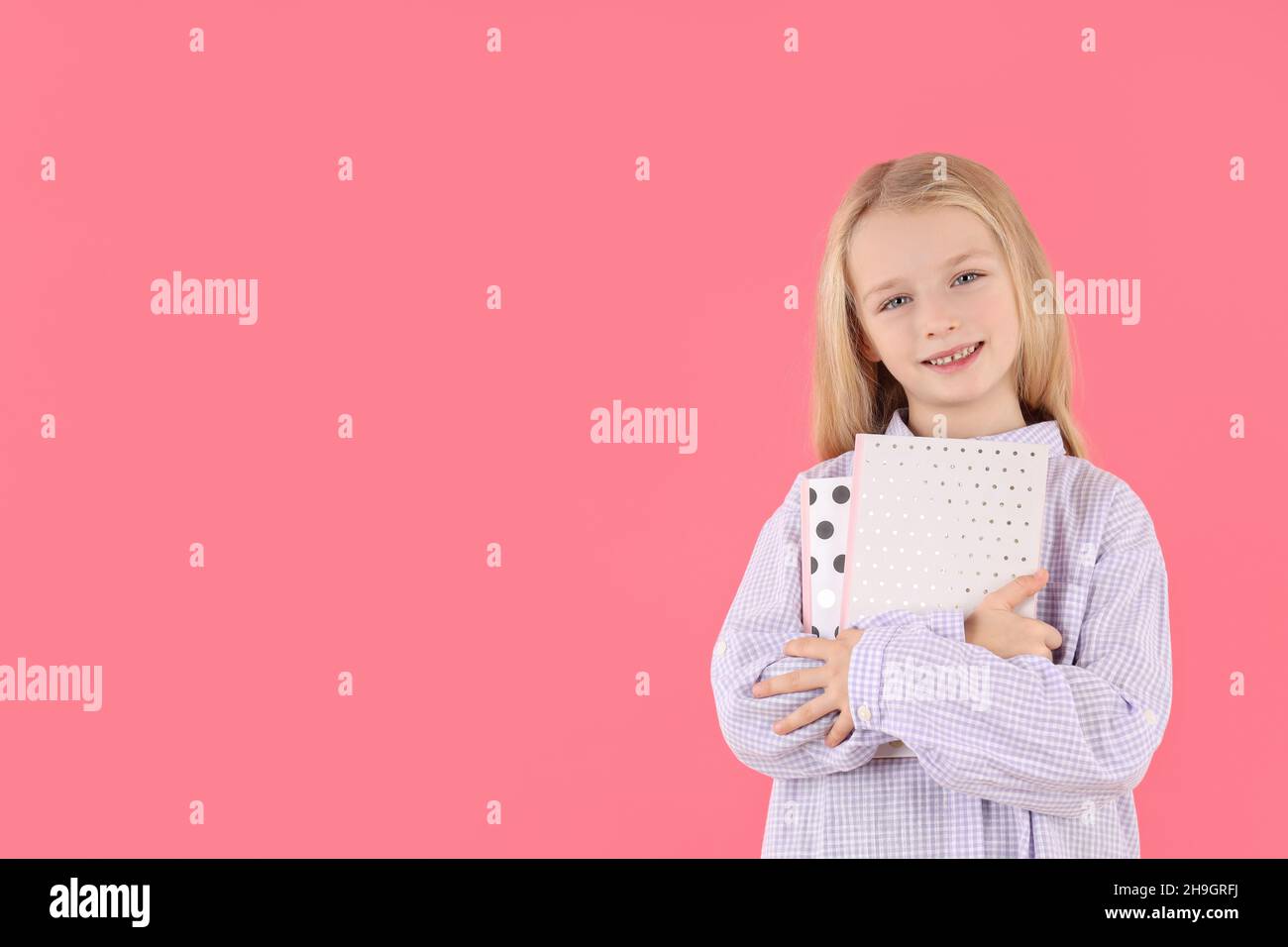 Cute little girl with notebooks on pink background Stock Photo - Alamy