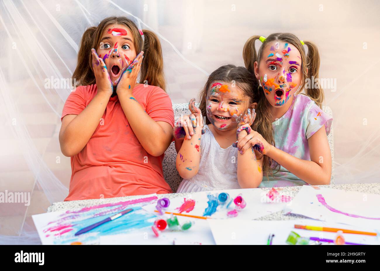 three children paint with paints. girls smile happily and make fun ...