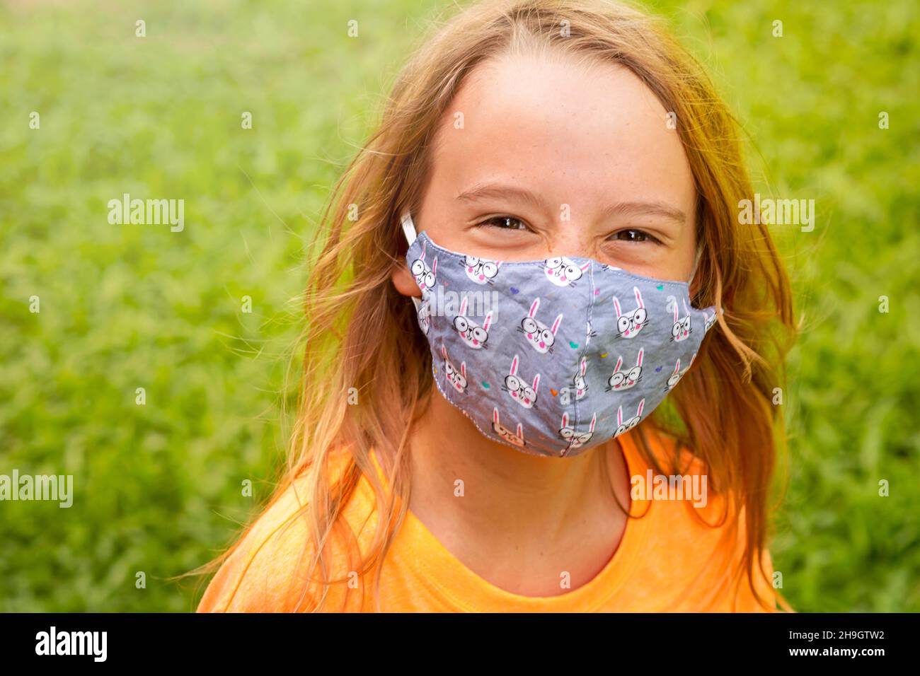 happy girl in a child's face mask smiling. child walks in the park ...