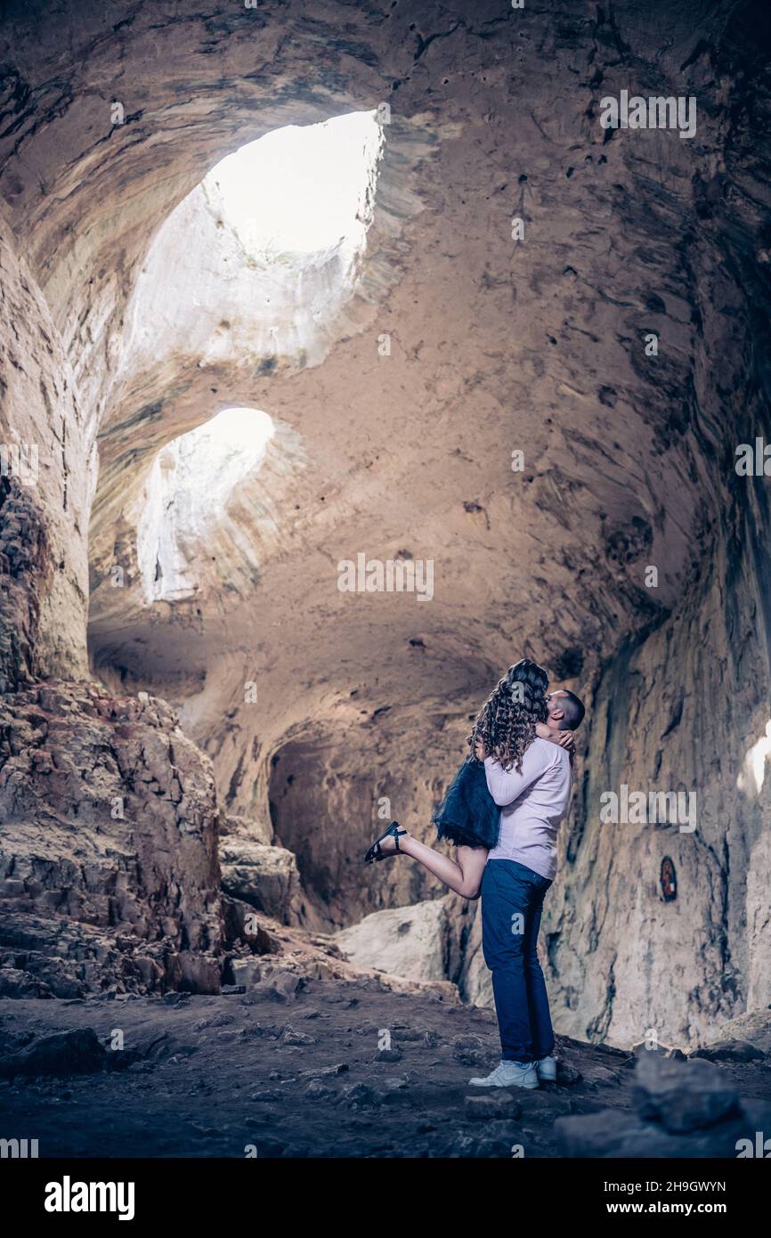 Bulgaria, circa 2021: Couple hugging in a natural cave. Cave holes look ...