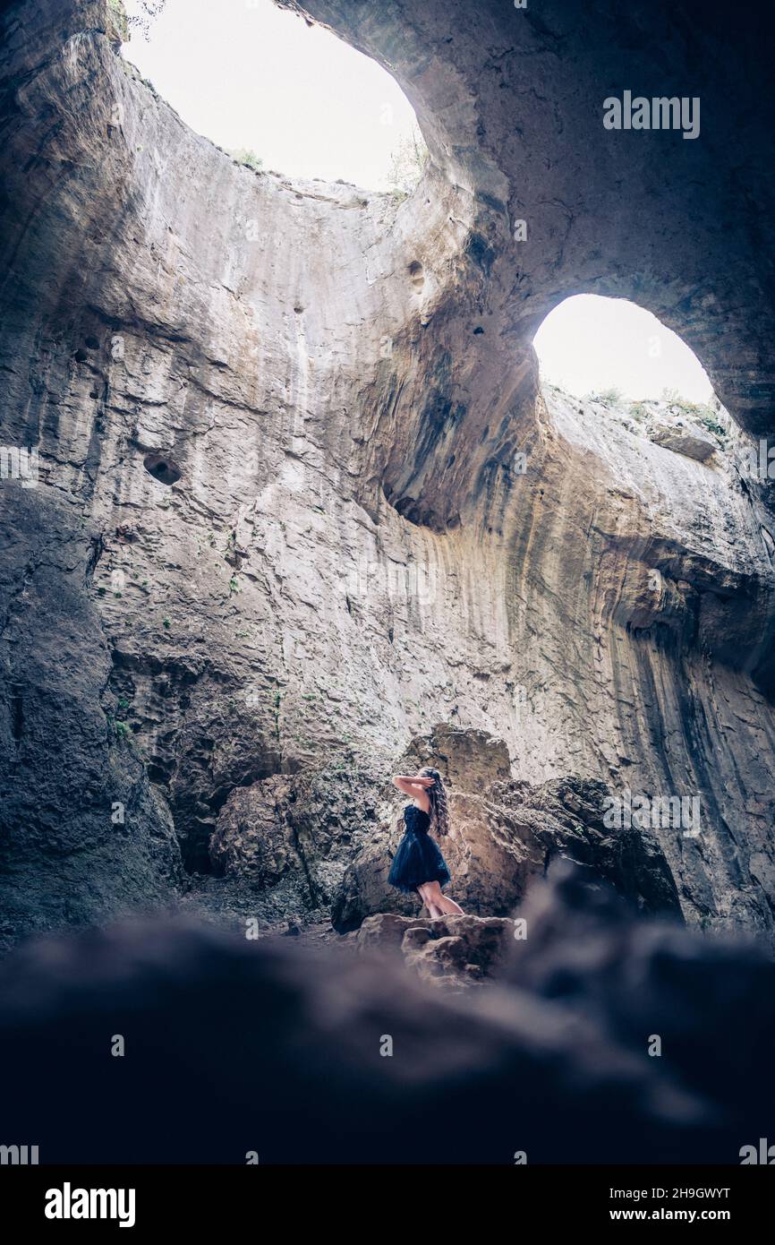 Bulgaria, circa 2021: Girl in a black dress stands in a natural cave ...