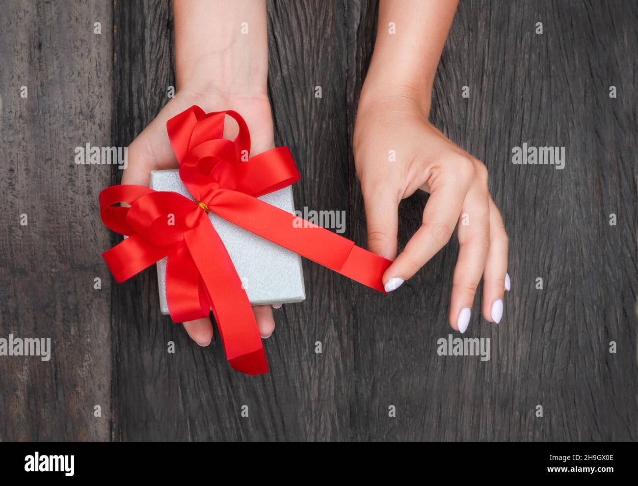 Hand is holding a gift box with a red ribbon hi-res stock photography ...