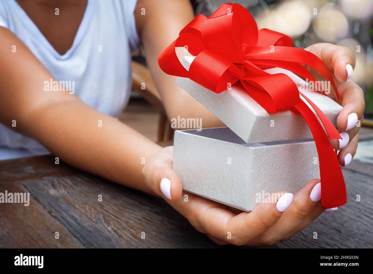 female hands open the light gift box with the red bow Stock Photo - Alamy