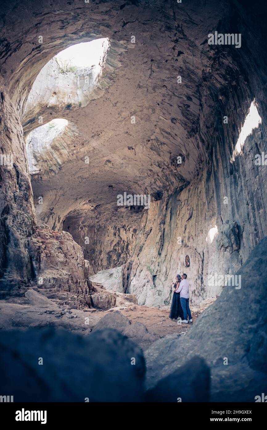 Bulgaria, circa 2021: Couple hugging in a natural cave. Cave holes look ...