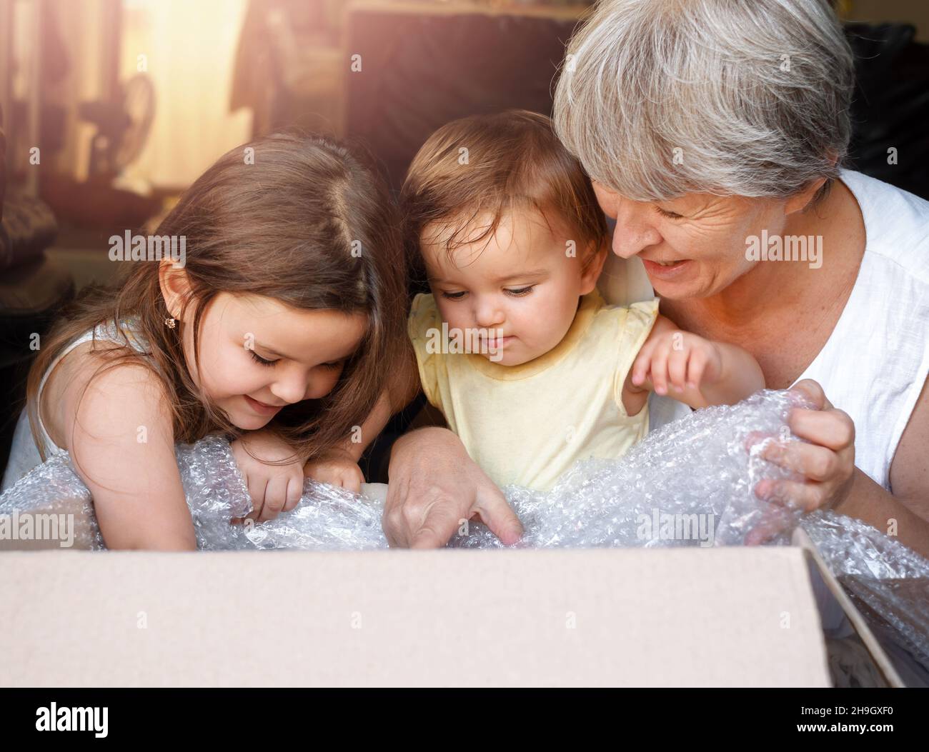 children and grandmother open the box. woman and granddaughters look ...