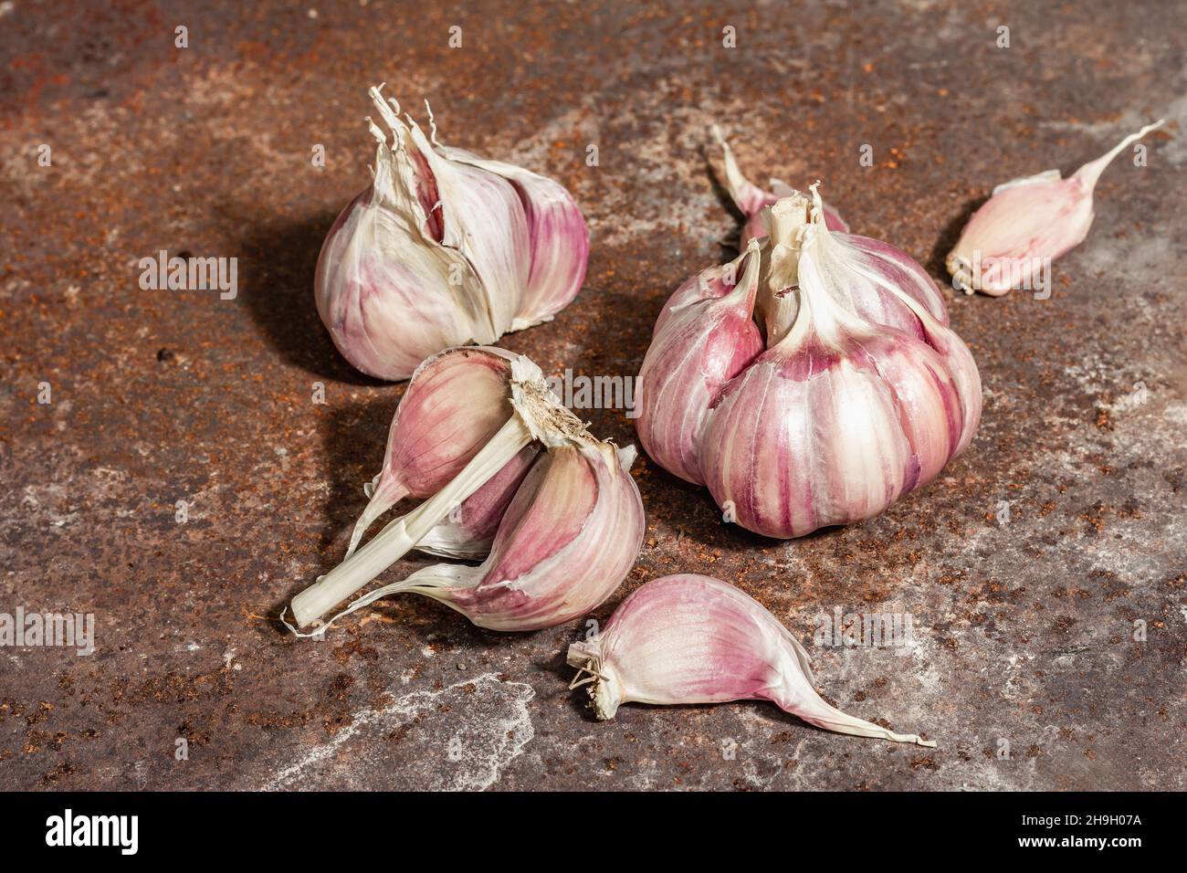 Fresh ripe garlic cloves on a rusty metal background, close up. Trendy ...