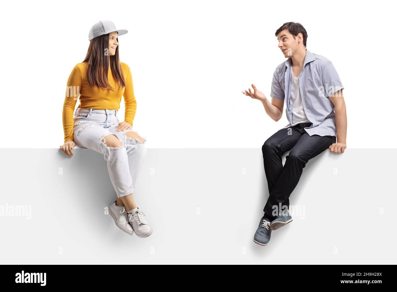 Casual young people sitting on a blank panel and having a conversation ...
