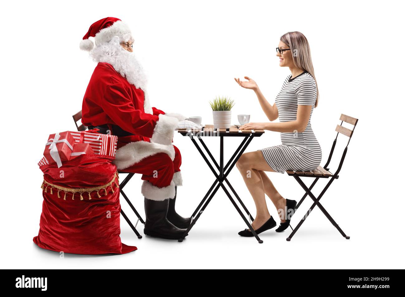 Santa Claus and a young woman drinking coffee and sitting in a cafe ...