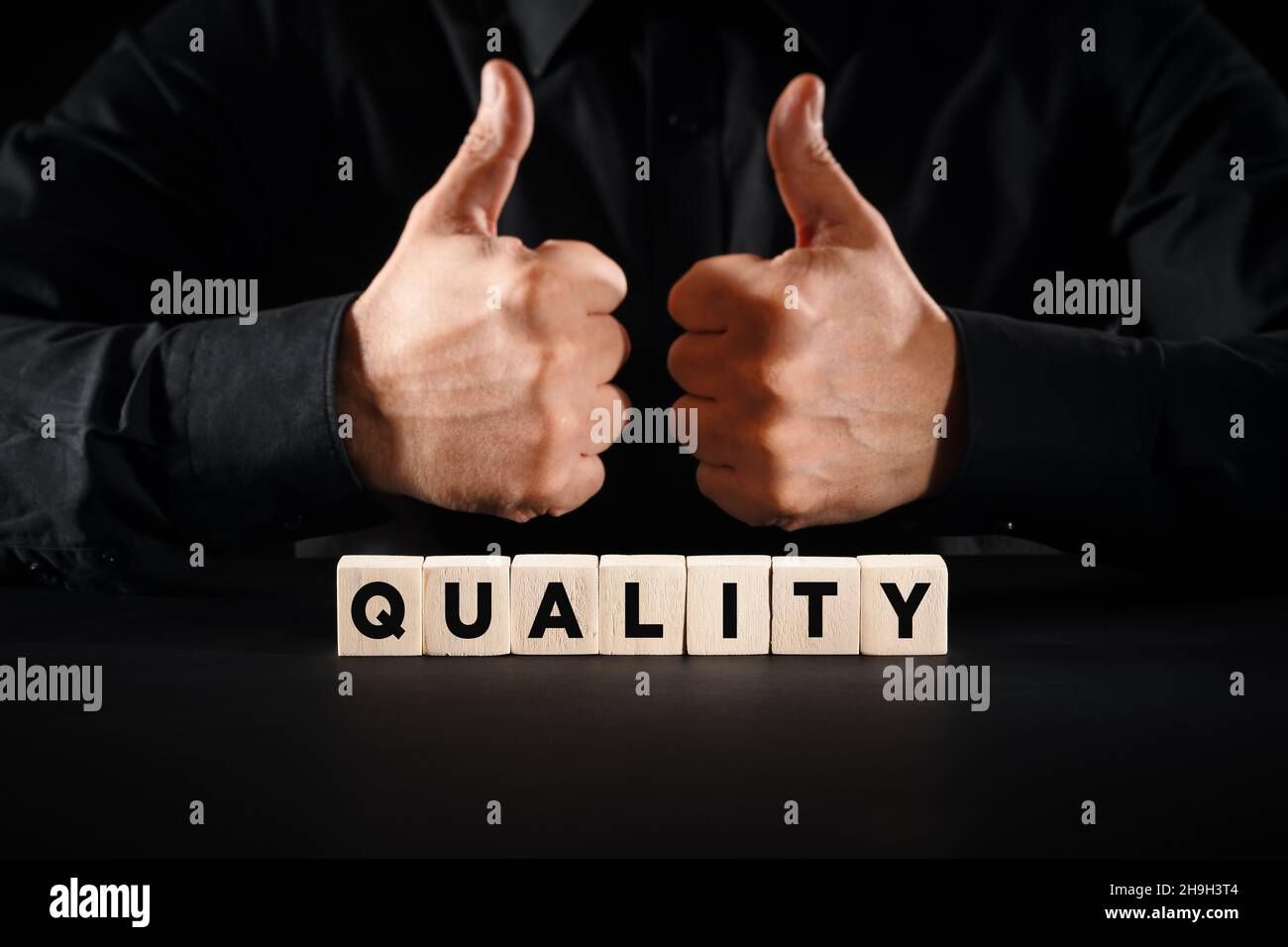 The word quality on wooden blocks with thumbs up male hand background ...