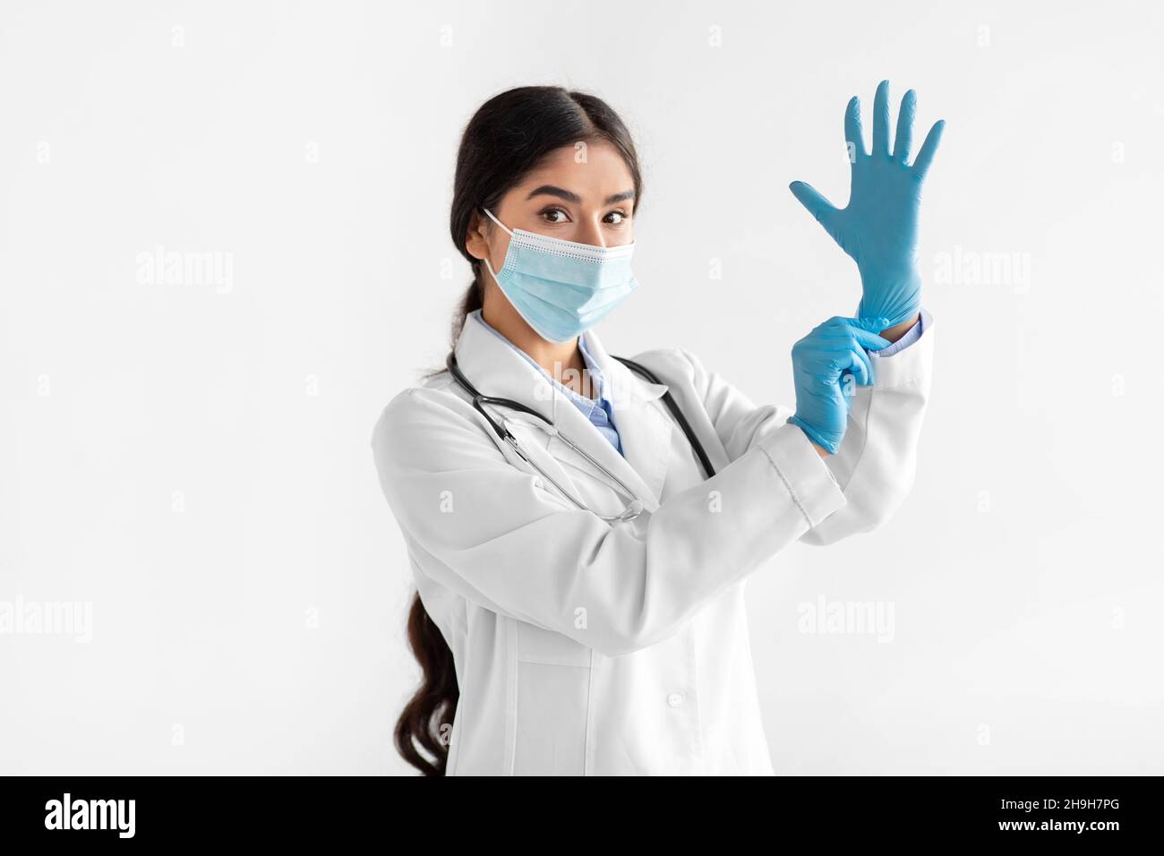 Serious Millennial Indian Female Doctor In Coat And Protective Mask