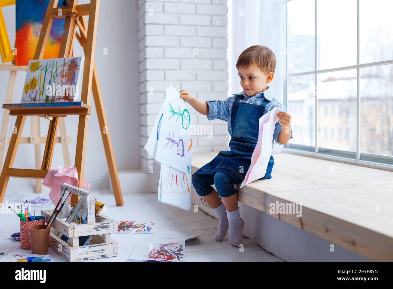 Cute, happy, white boy in blue shirt and jeans sitting with palette in ...