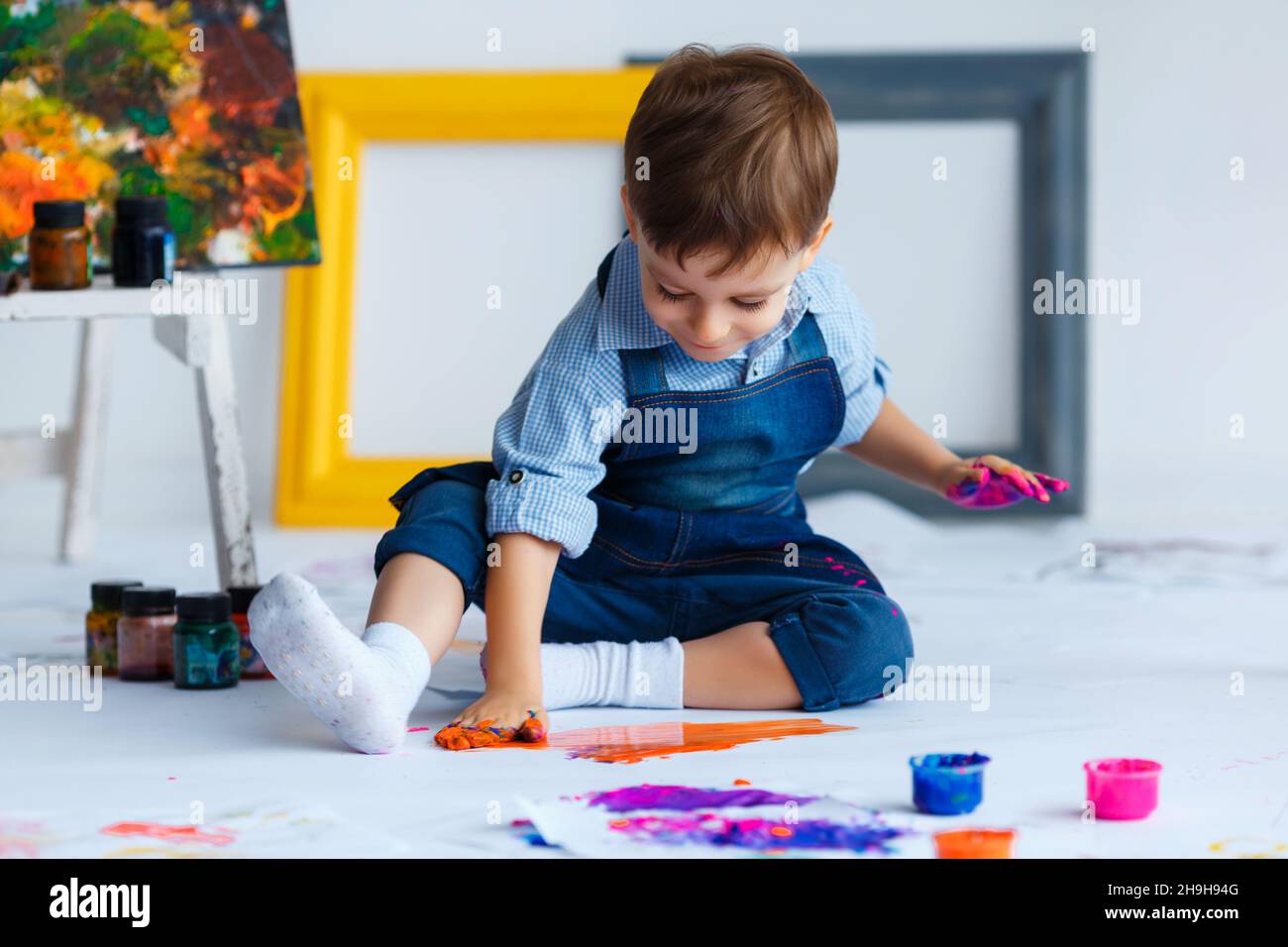 Cute, happy, white boy in blue shirt and jeans drawing with bright ...