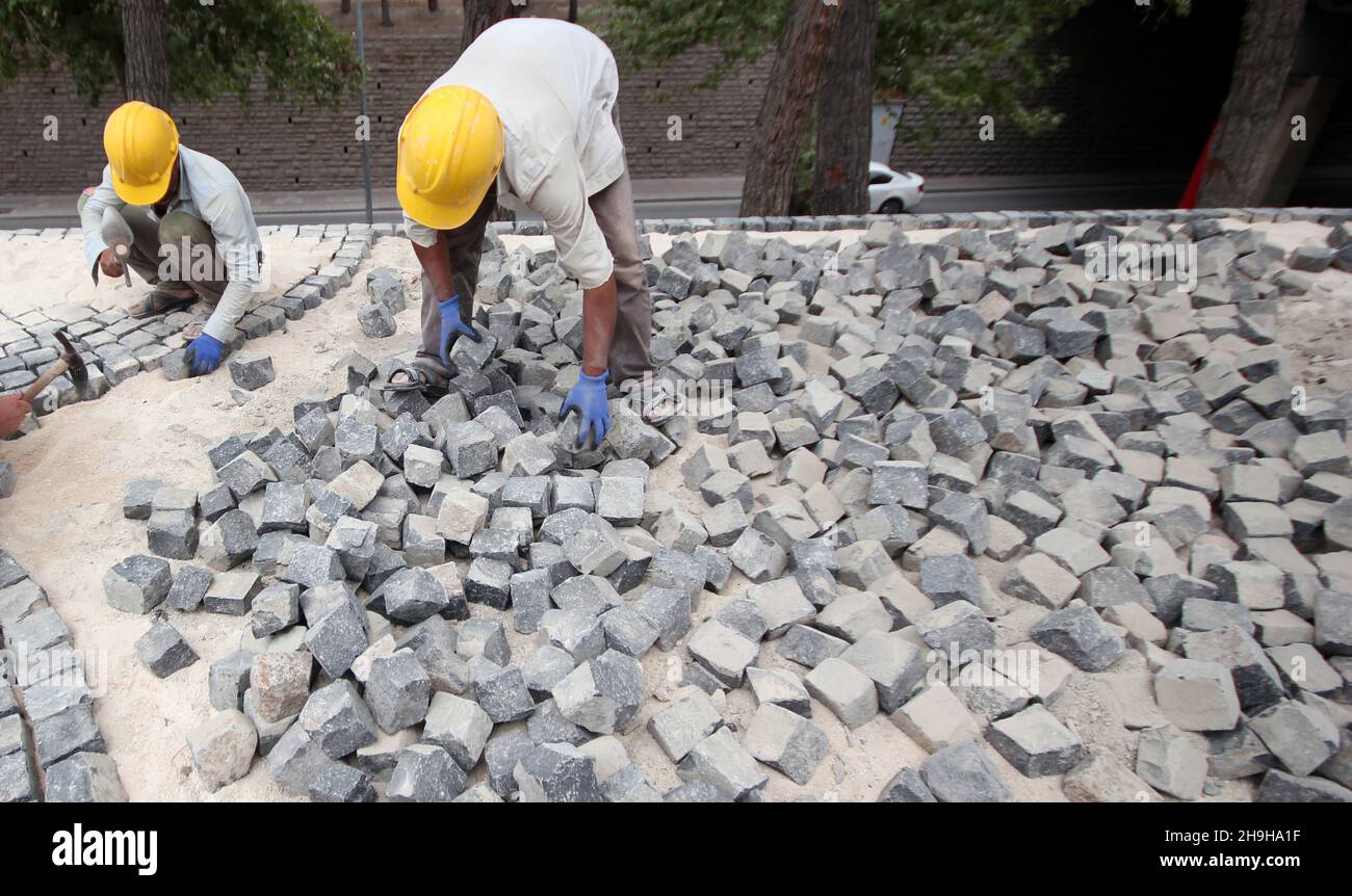 Workers laying cobblestone. Construction zone Stock Photo - Alamy