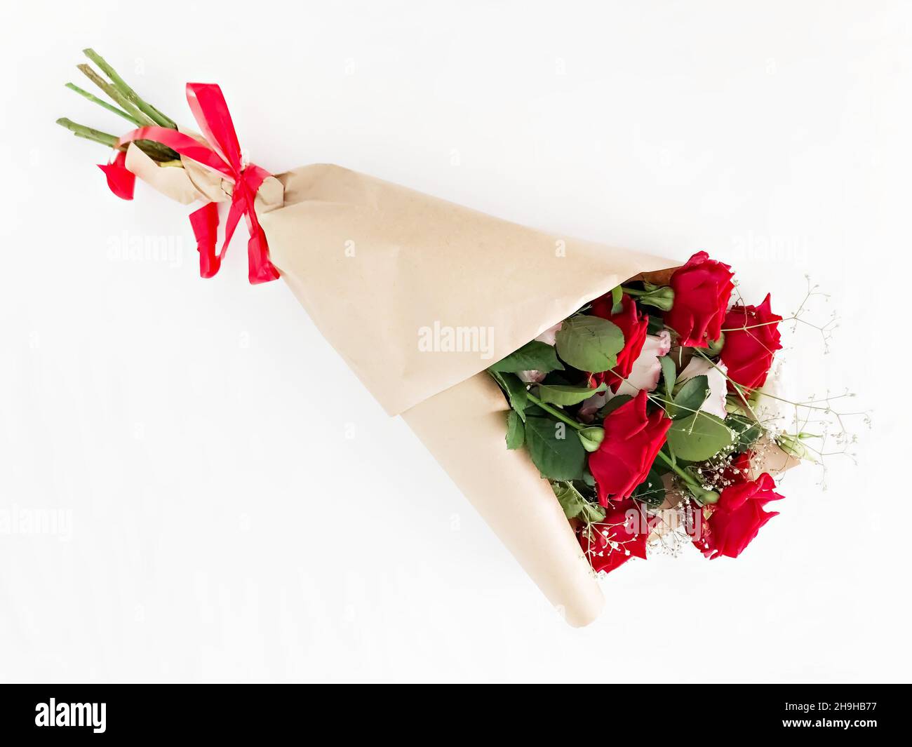 Red roses wrapped in brown kraft paper and tied with a red ribbon on a ...