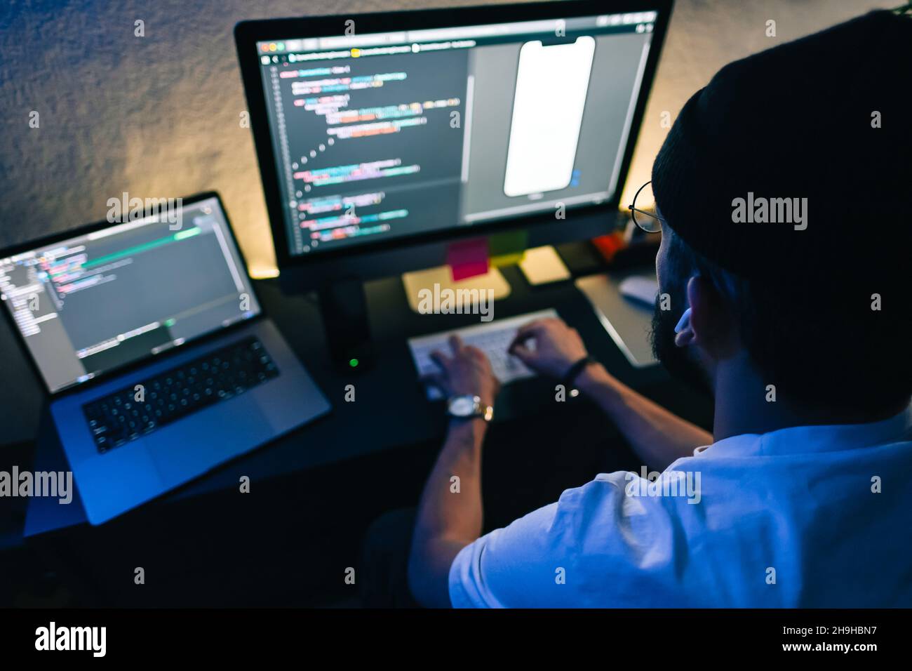 Young Man Mobile Developer Writes Program Code On A Computer Programmer Work In Home Office