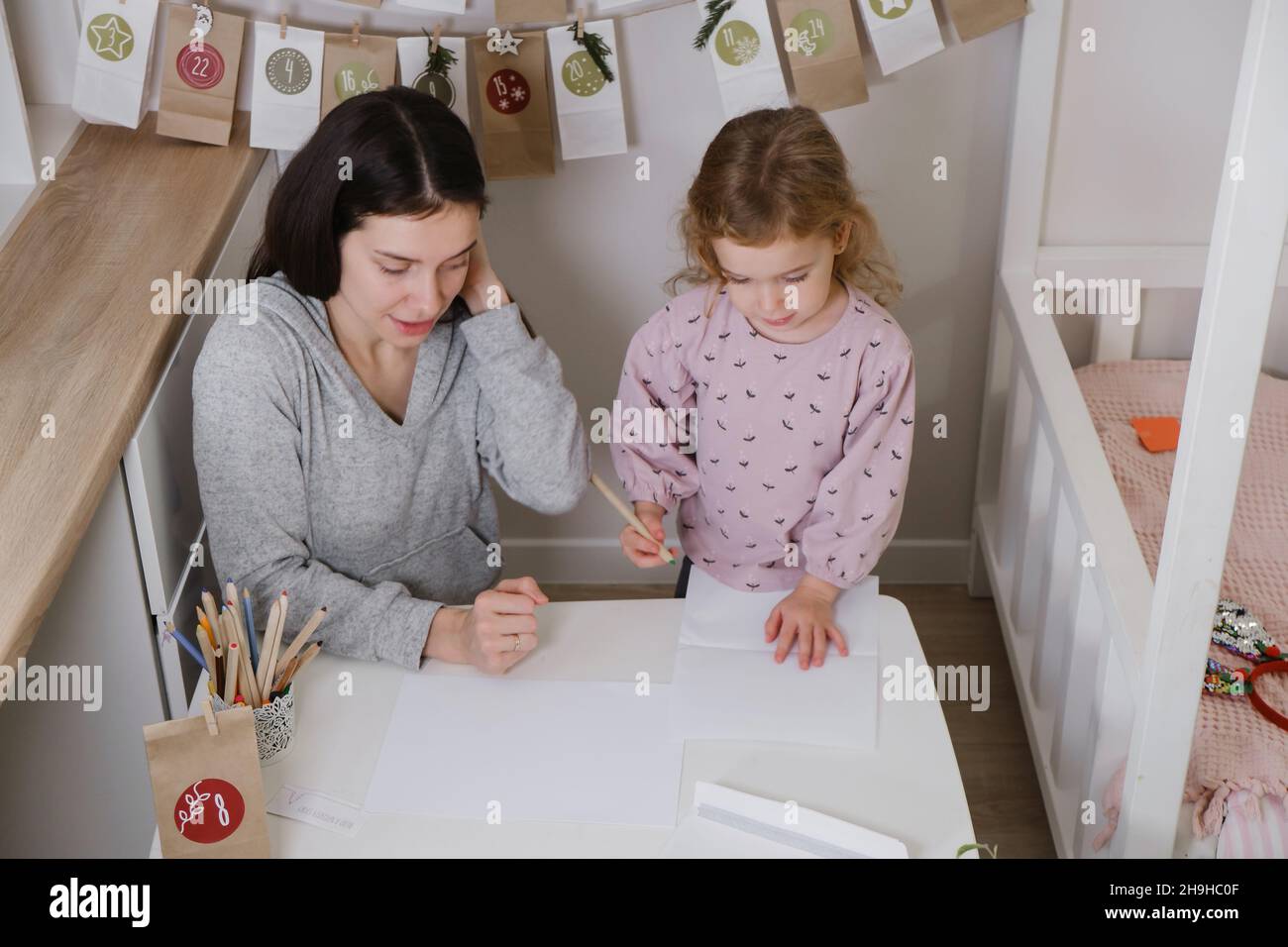 Mother with toddler child writing Christmas letter and doing advent ...