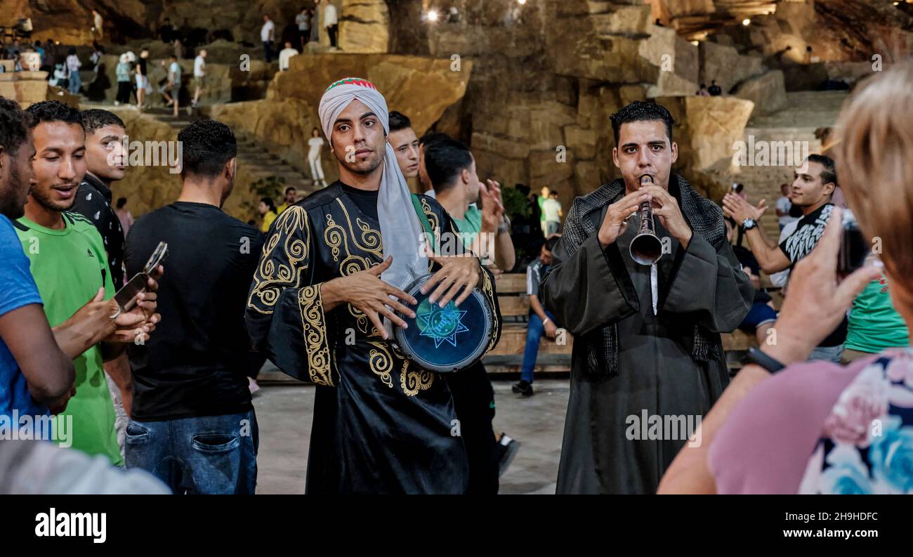 Two young Egyptian playing folk instruments on town square in evening ...
