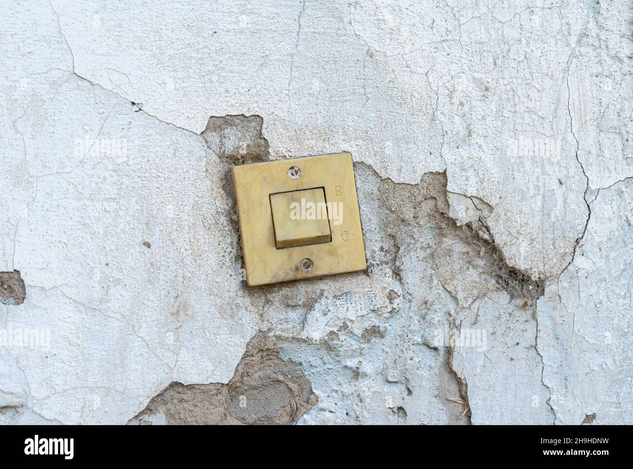 Plastic light switch on a wall with disintegrated plastering showing ...