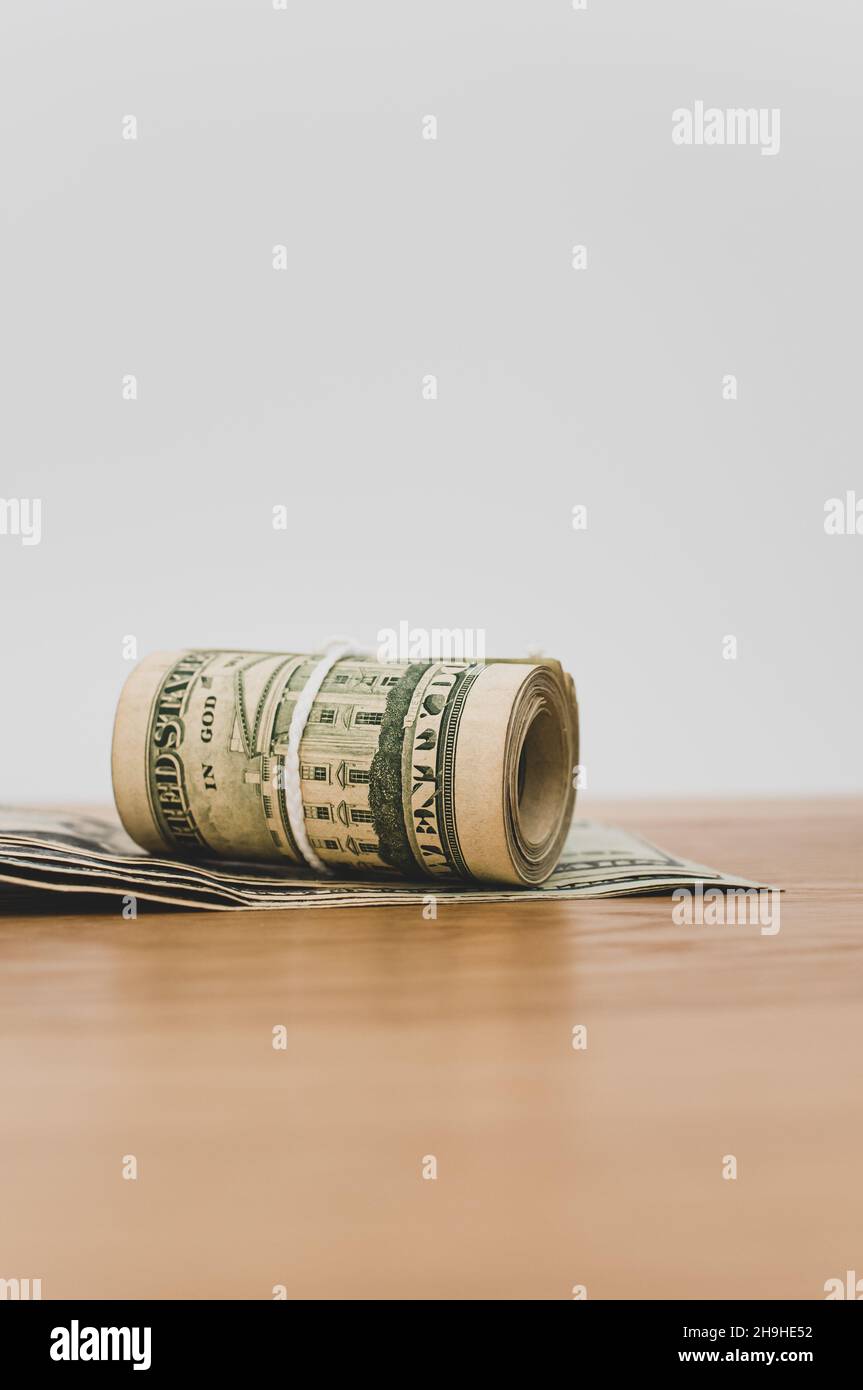 isolated US dollar banknotes roll on a wooden background with text ...