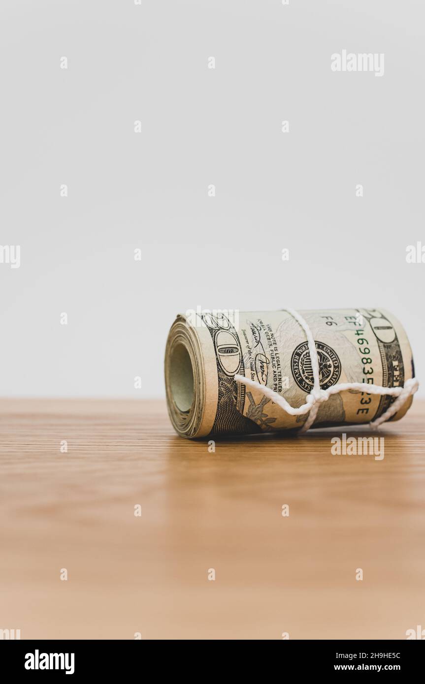 isolated US dollar banknotes roll on a wooden background with text ...