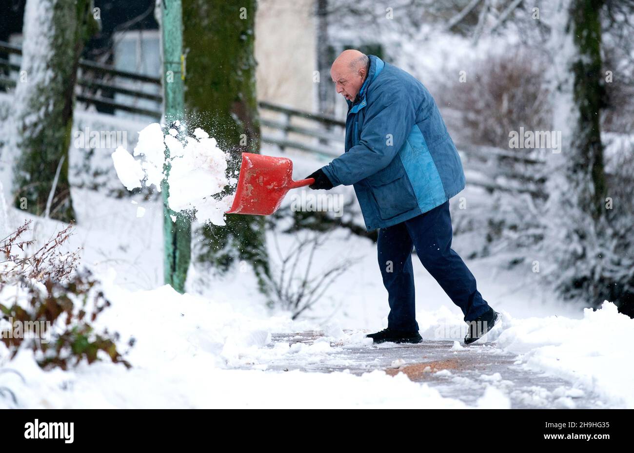 A man clears snow away in Leadhills, South Lanarkshire as Storm Barra ...