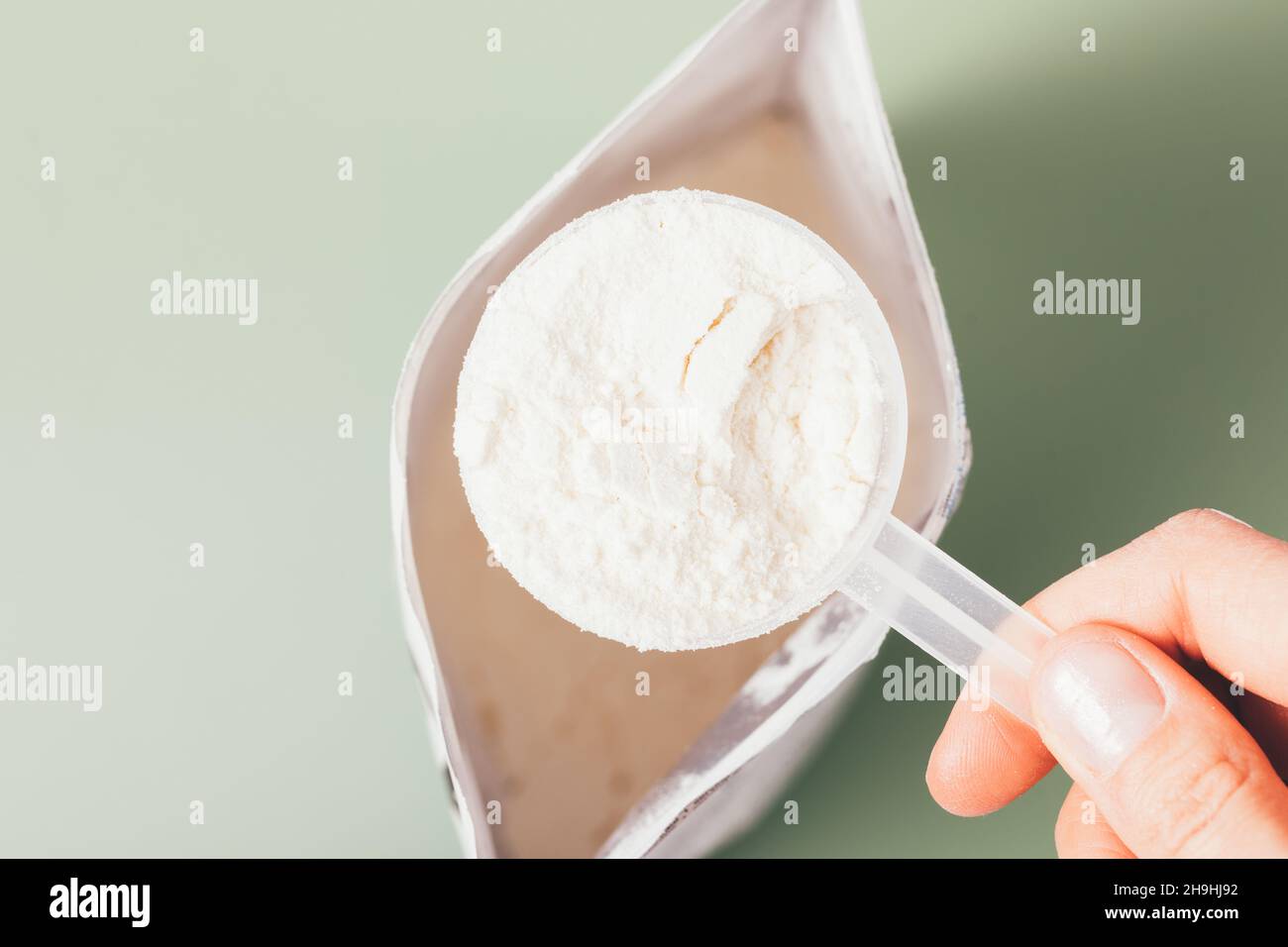 Protein powder measuring spoon in female hand over open package of ...