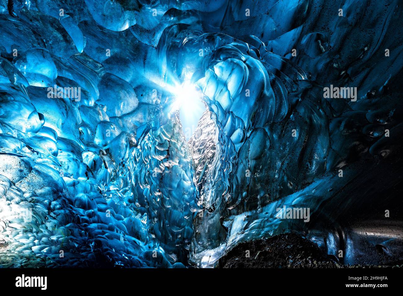 Blue glacial ice with hole through to the sky with sunburst, from an ...