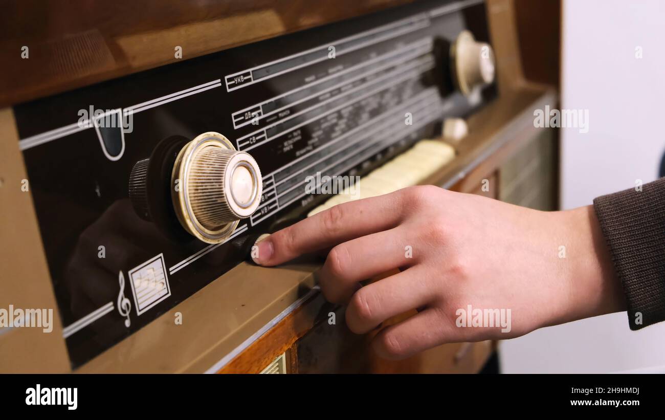 Close-up of man's hand rotating the knob on the old radio. Vintage ...