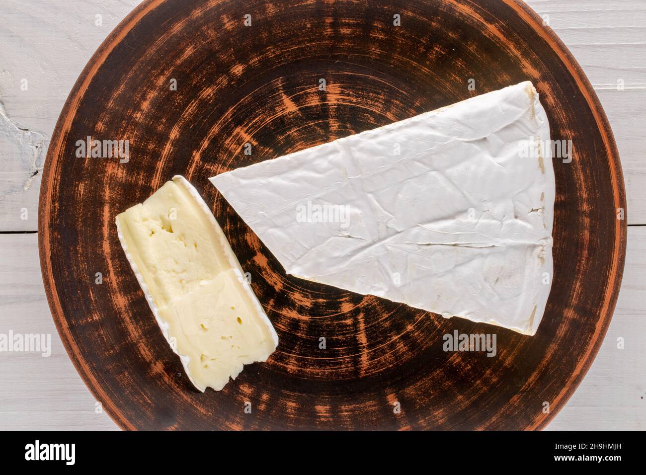 Two fragrant pieces of brie cheese on a clay platter, close-up, top ...