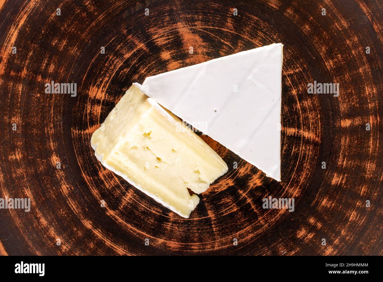 Two fragrant pieces of brie cheese on a clay platter, close-up, top ...