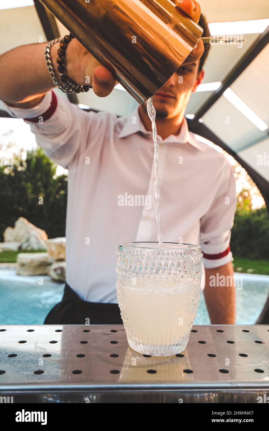 Professional Italian barman pouring cocktail into a glass from the ...