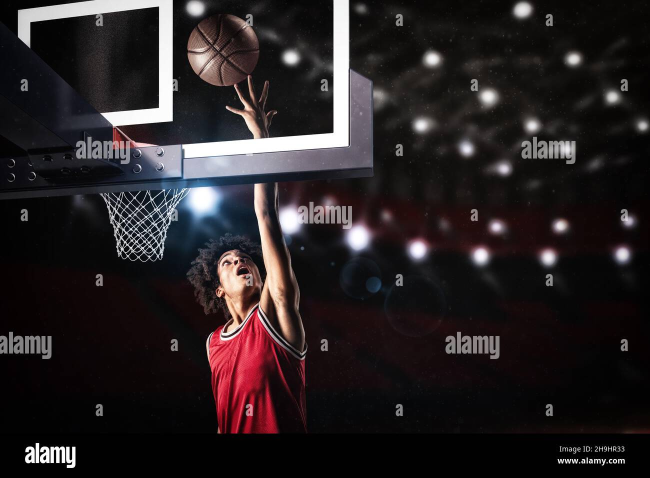 Basketball player in red uniform jumping high to make a slam dunk to ...